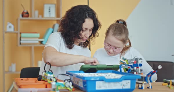 A teacher and a young girl student learn the technical basics of robot ...