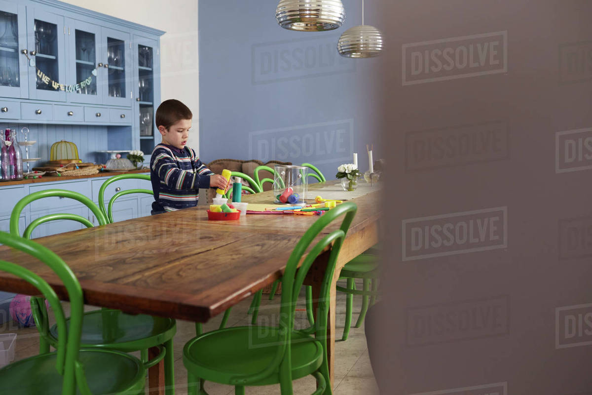 Young boy sitting at kitchen table and painting picture - Stock Photo ...