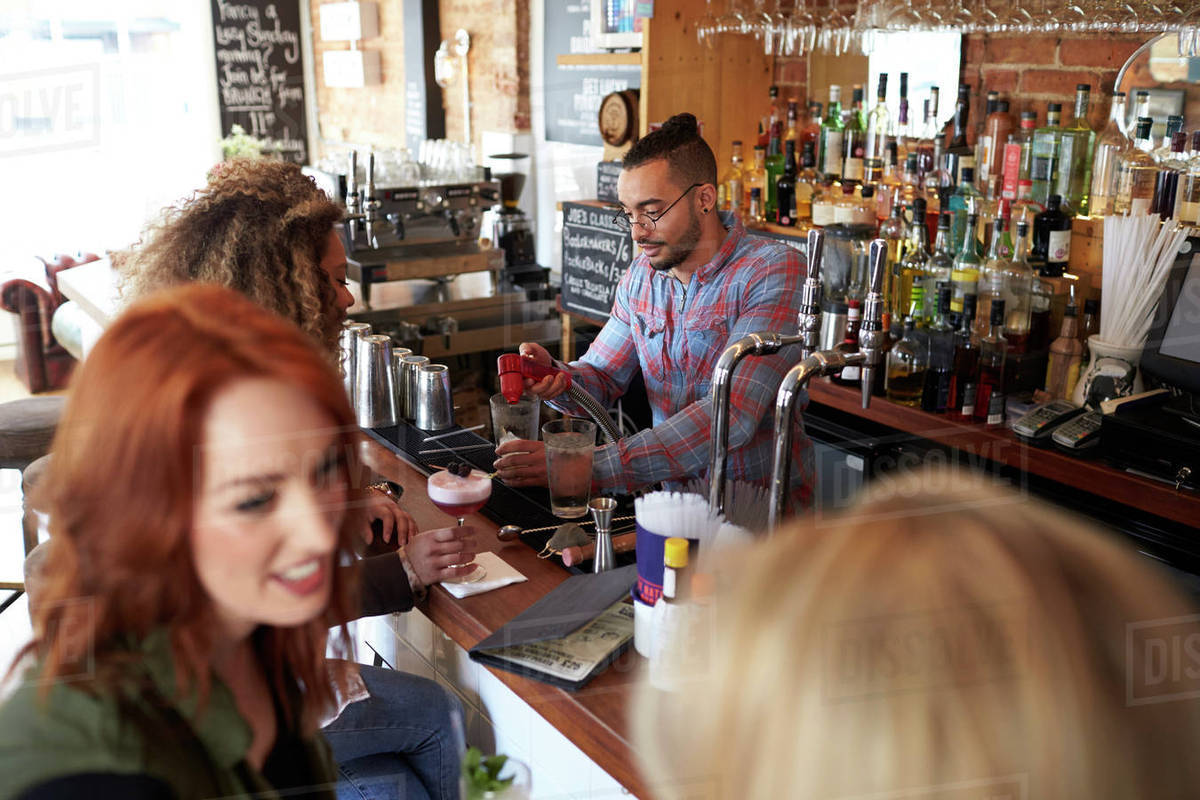 Bartender serving female customers in cocktail bar - Royalty-free Stock ...