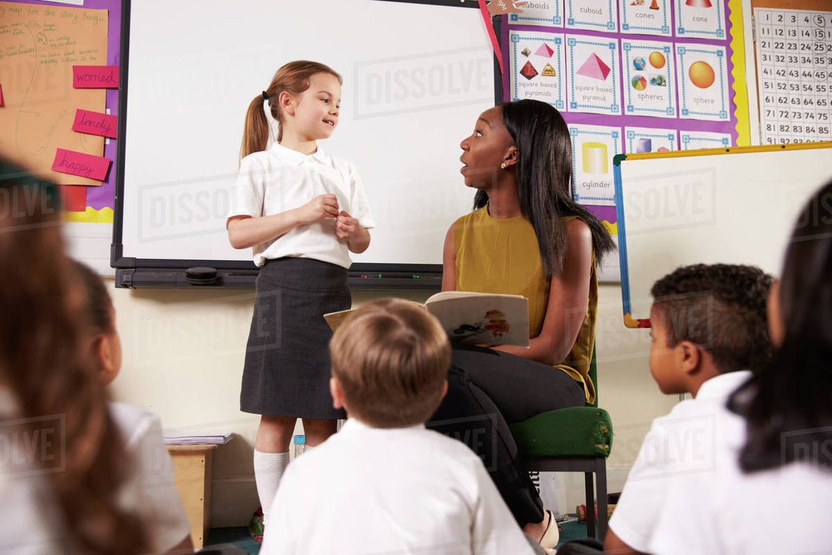Female elementary pupil reading in front of class - Stock Photo - Dissolve