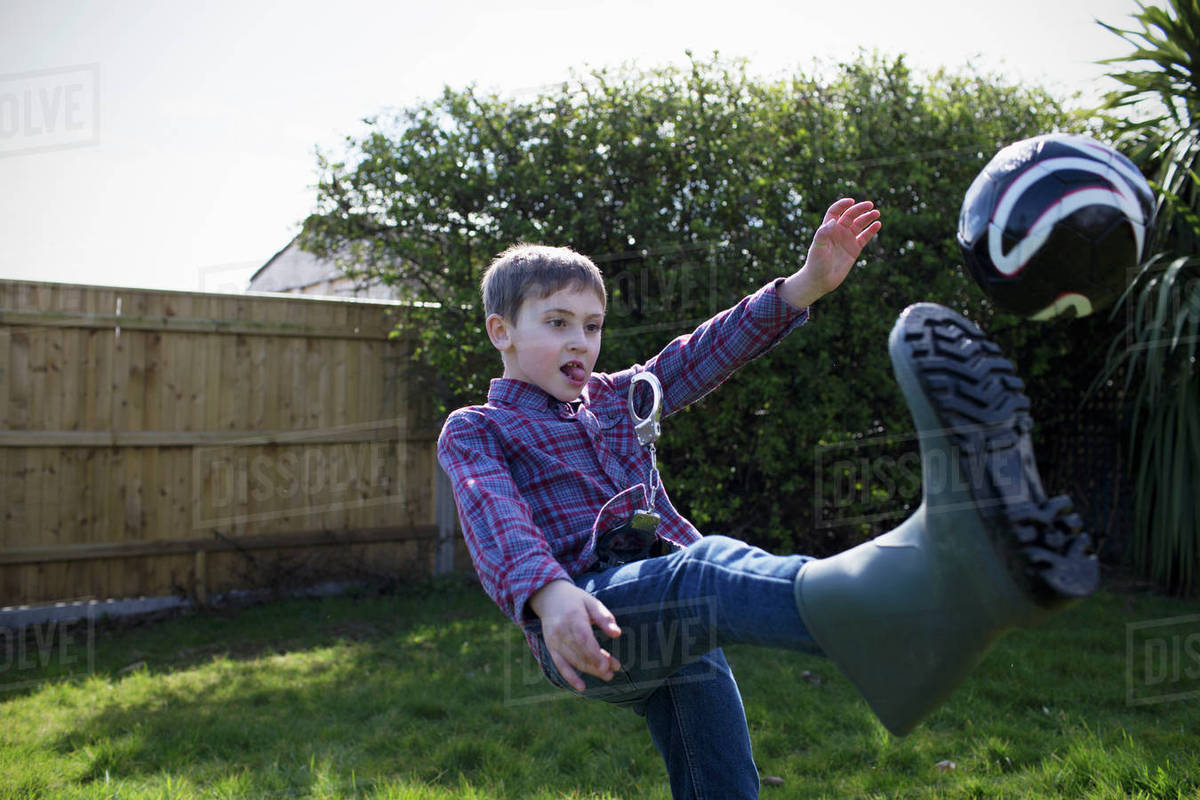 Young boy playing soccer in garden - Royalty-free Stock Photo | Dissolve