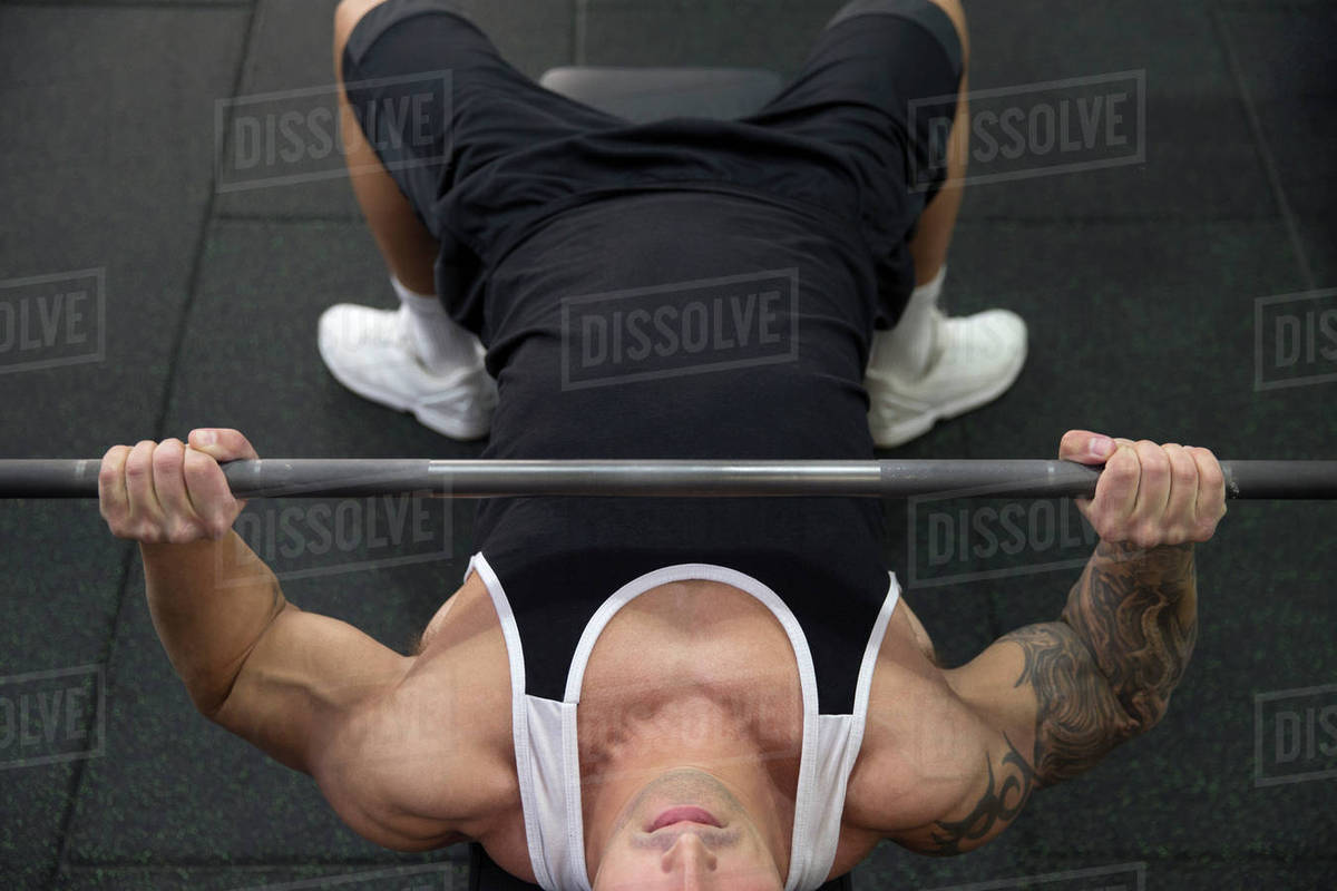 Overhead view of young man bench pressing weights in gym - Royalty-free ...