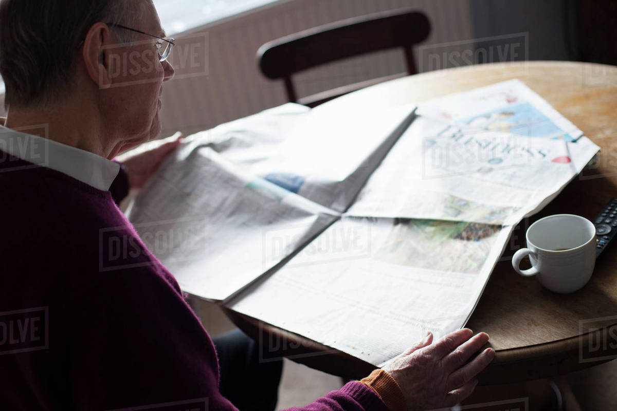 Senior man looking through newspaper at home - Royalty-free Stock Photo ...