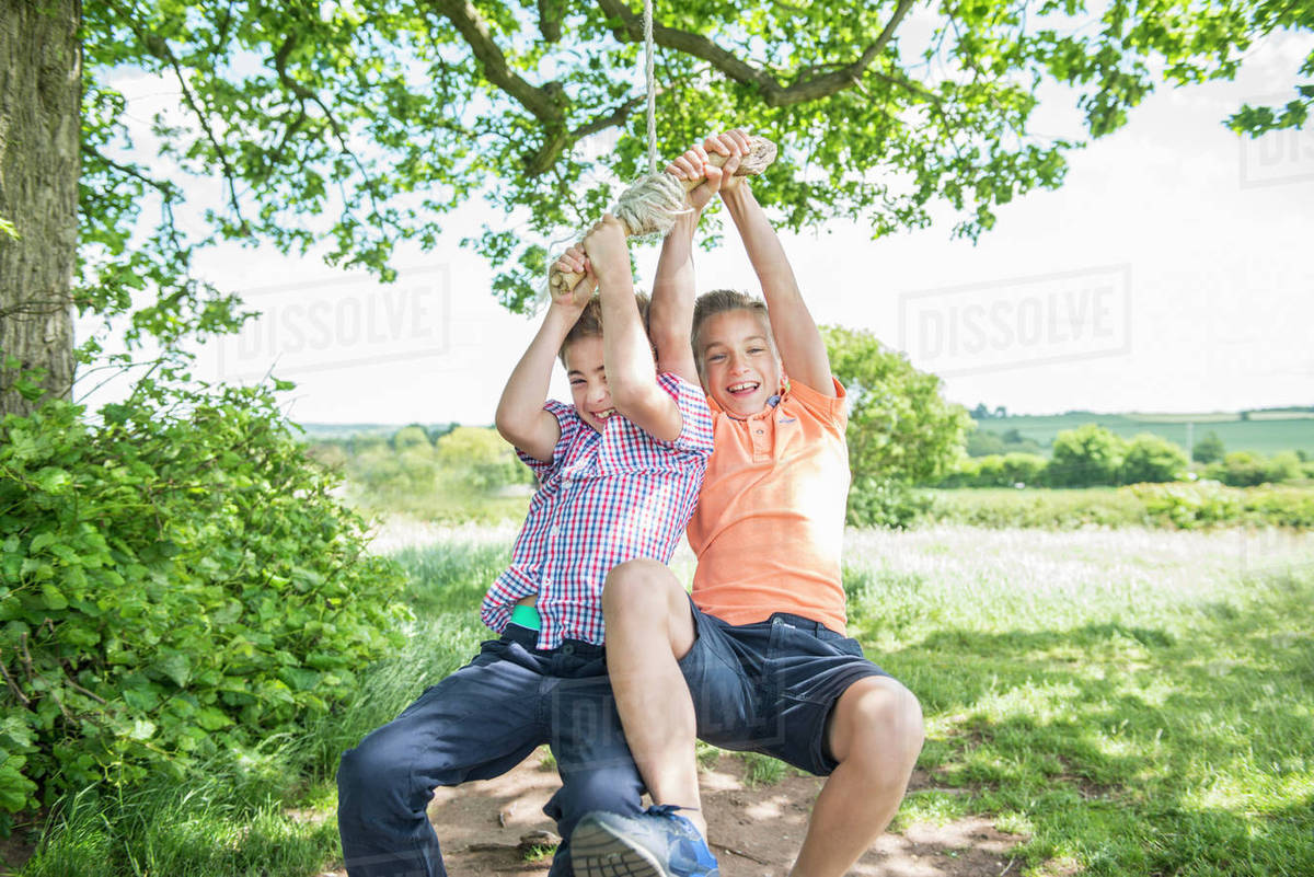 Two boys playing on a swing in the countryside - Royalty-free Stock ...