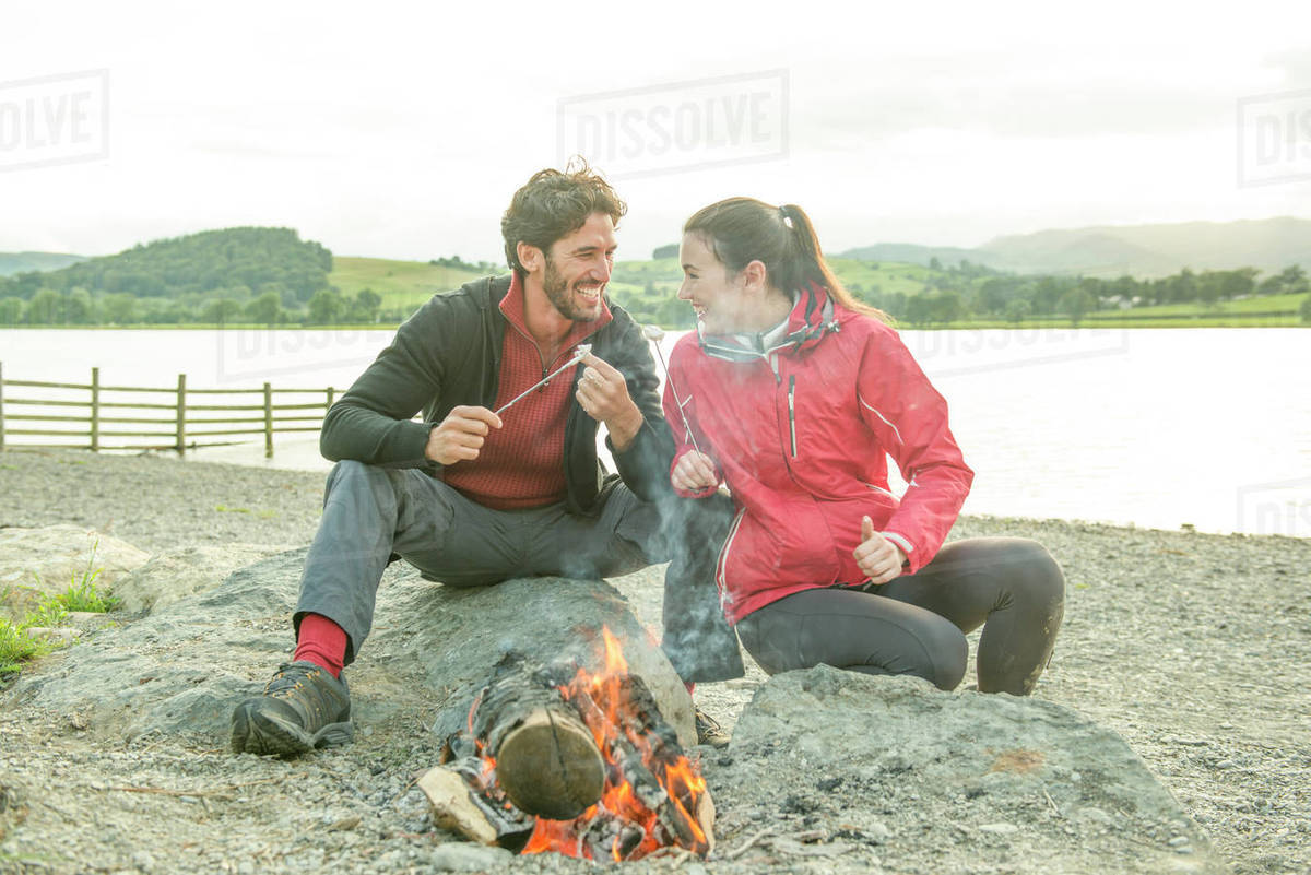 Three friends relax around a campfire on the shore of Bala Lake in ...