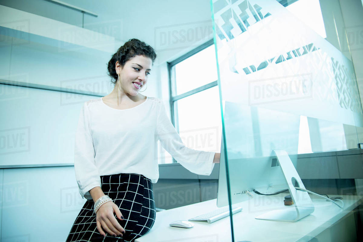 A professional woman sitting in front of a computer in an office ...