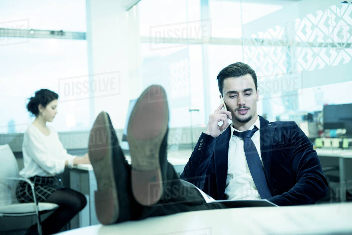 A professional man making a phone call in an office environment ...