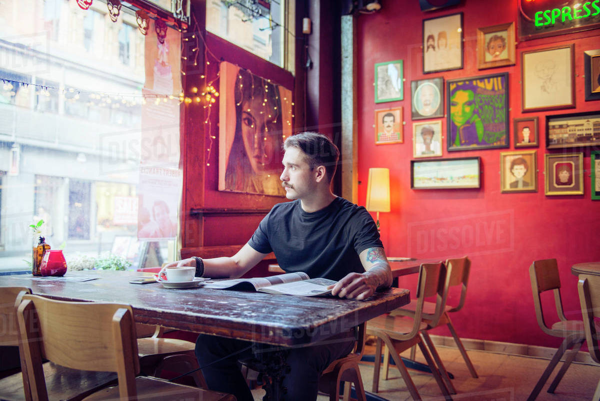 A young man sitting at a table in a coffee shop in Manchester - Royalty ...