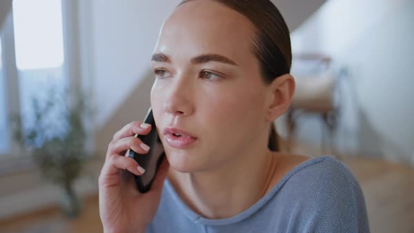 Serious girl calling mobile phone at home closeup. Calm lady talking ...