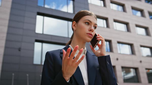 Nervous lady talking mobile phone at business street closeup. Woman ...