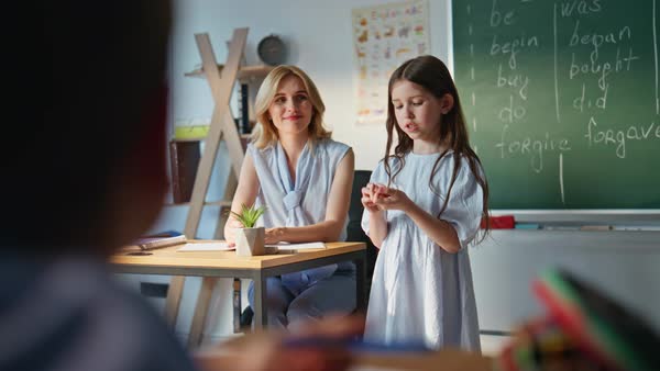 Little girl counting blackboard at elementary school lesson. Woman ...