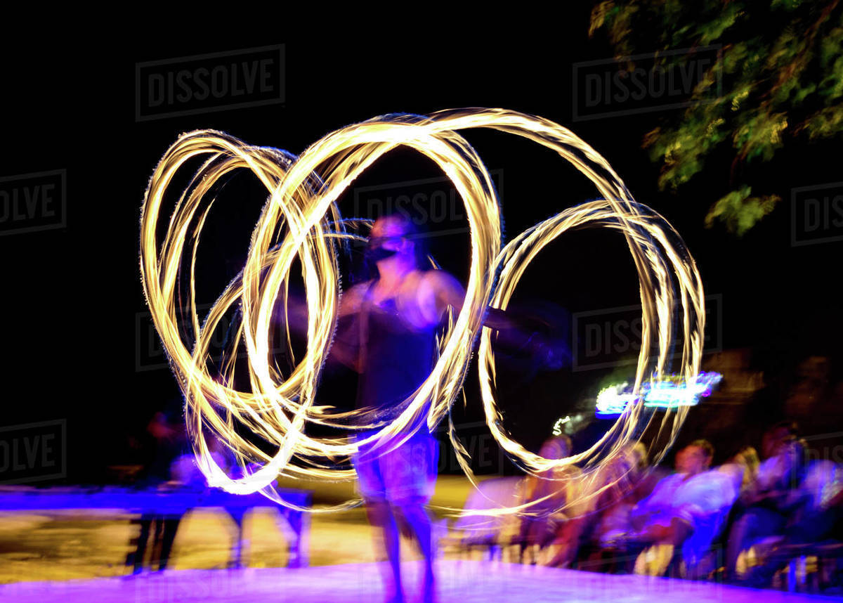 Man making fire show performance in the night with chains pending balls ...