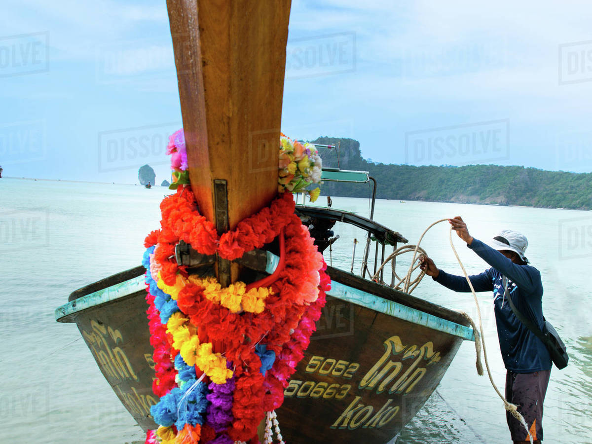 Captain of a traditional Long tail boat removing the rope to sail ...