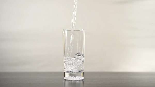 Pouring glass of water in slow motion until it overflows. Overfilling ...