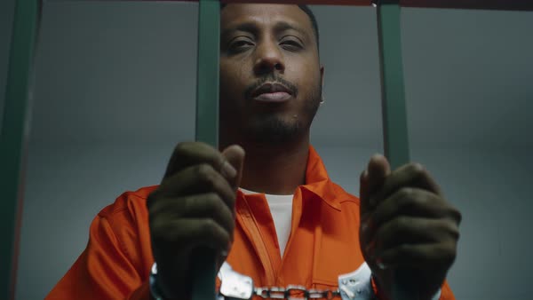 Prisoner keeps hands on jail cell bars and looks at camera - 4K Royalty ...