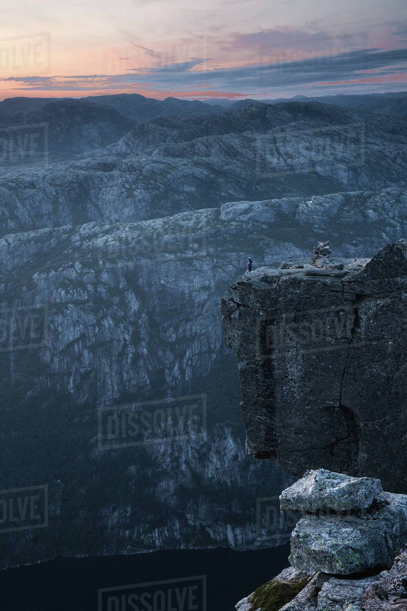 Woman looking at view while standing on top of cliff during sunset ...