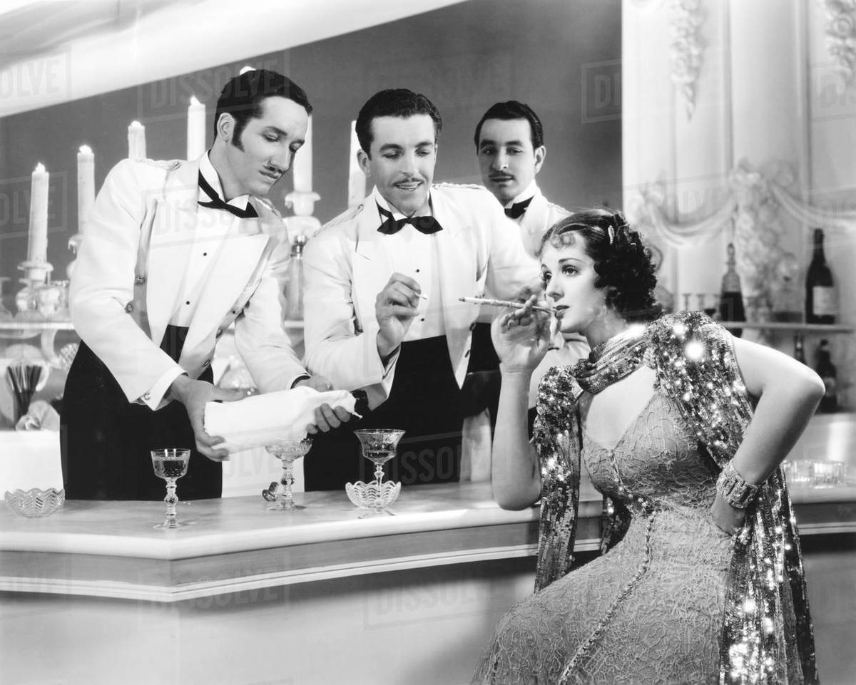 Two overly attentive waiters light a woman's cigarette and pour her ...