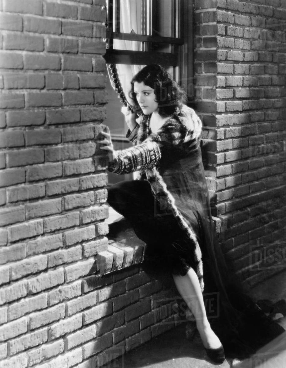 Woman trying to escape through a window - Stock Photo - Dissolve