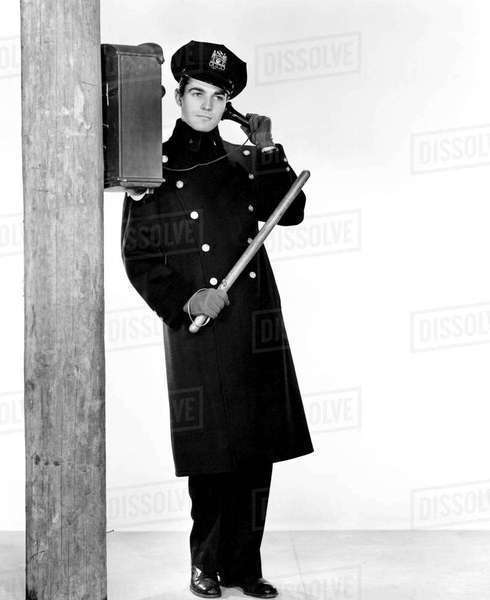 Police officer holding a nightstick and talking on a phone - Royalty ...