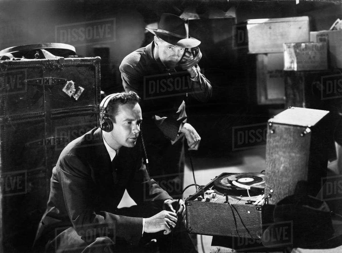 Two men listening to a recording with earphones - Stock Photo - Dissolve