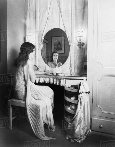 Woman sitting at her vanity table smiling into the mirror - Royalty ...