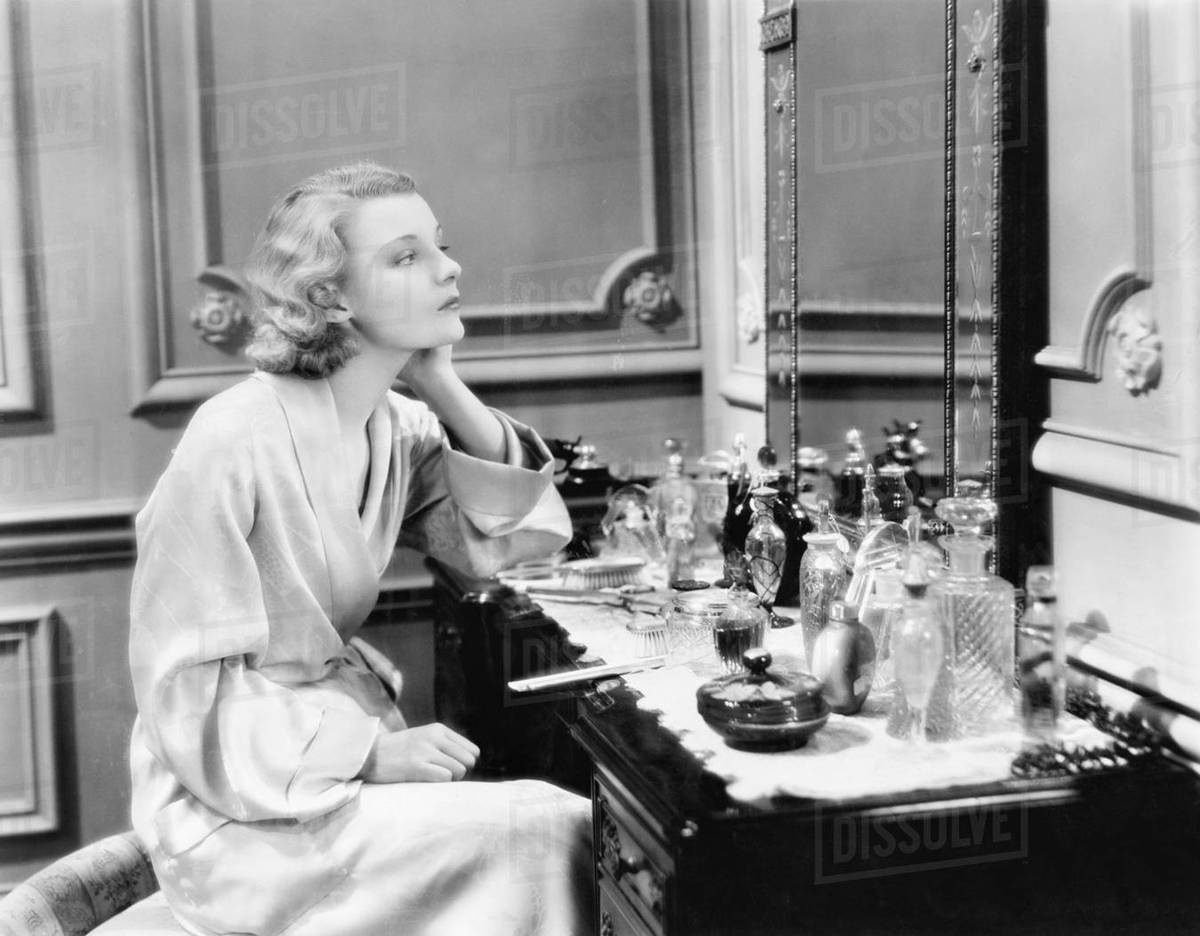 Woman sitting at her vanity looking into the mirror - Stock Photo ...