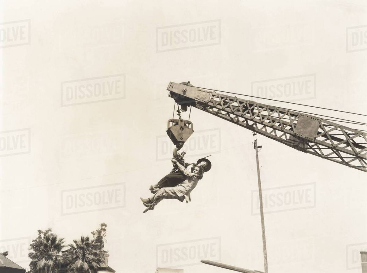 Two people dangling from crane - Stock Photo - Dissolve