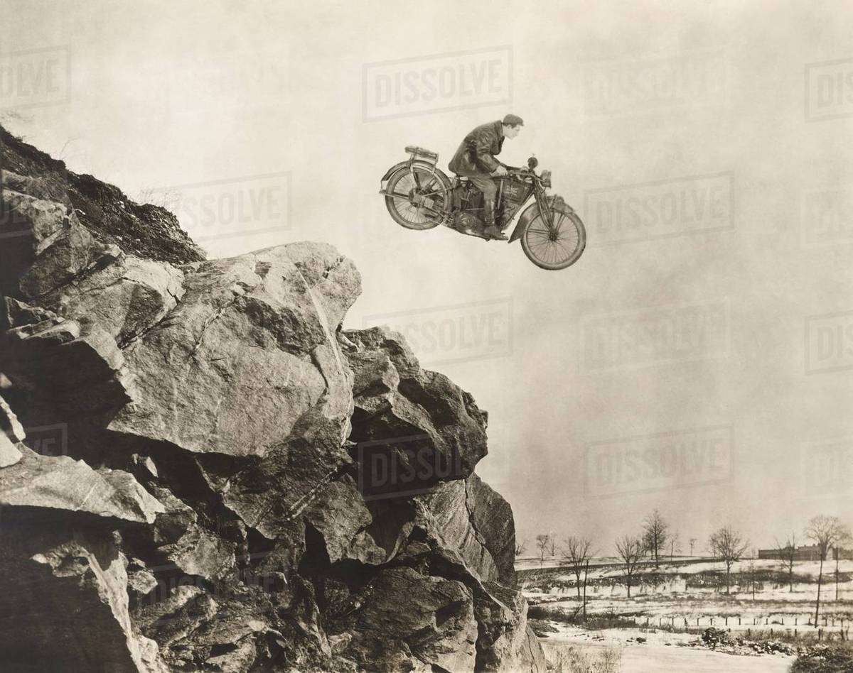 Stuntman on motorbike flying over cliff - Stock Photo - Dissolve