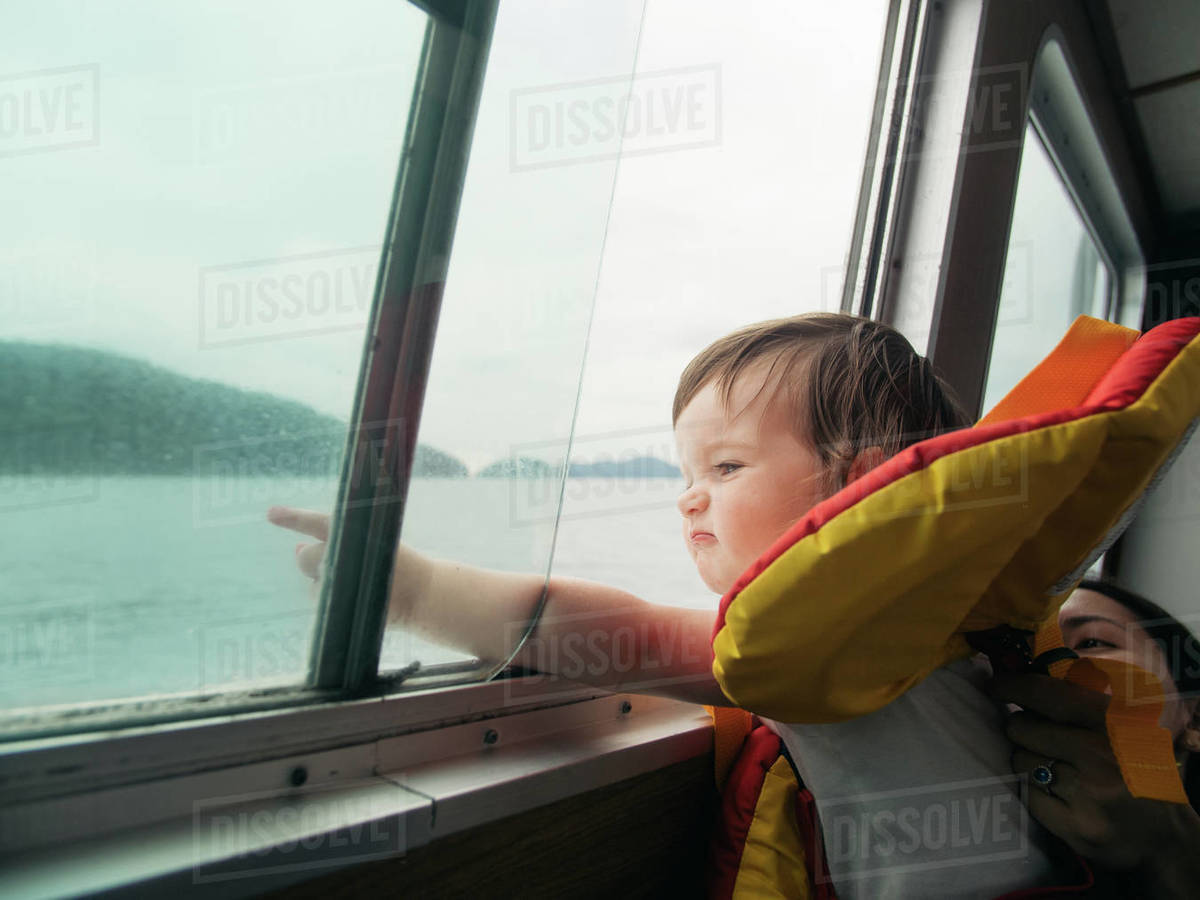 Toddler looking out boat window 5 - Stock Photo - Dissolve