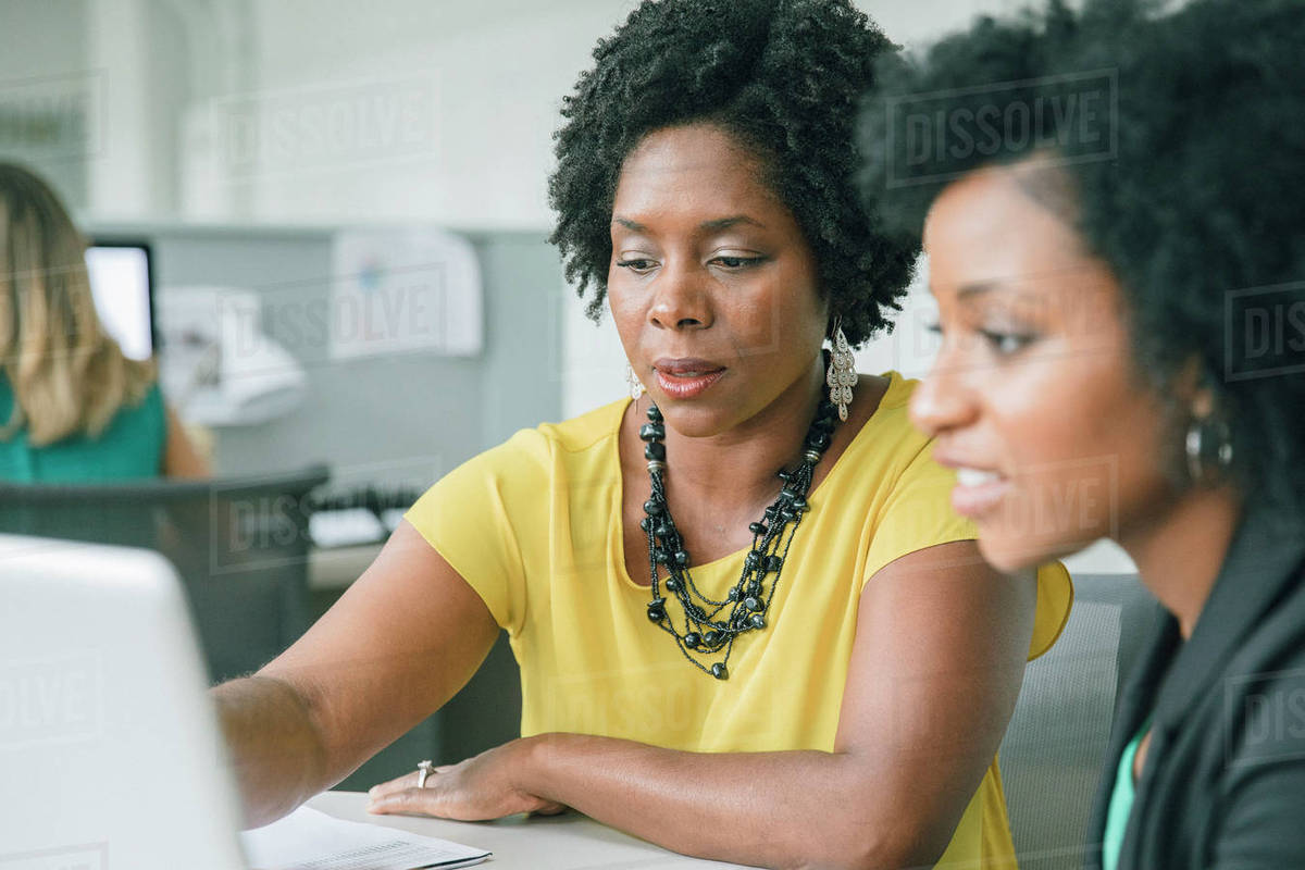 Two female coworkers working on a laptop in an office - Royalty-free ...