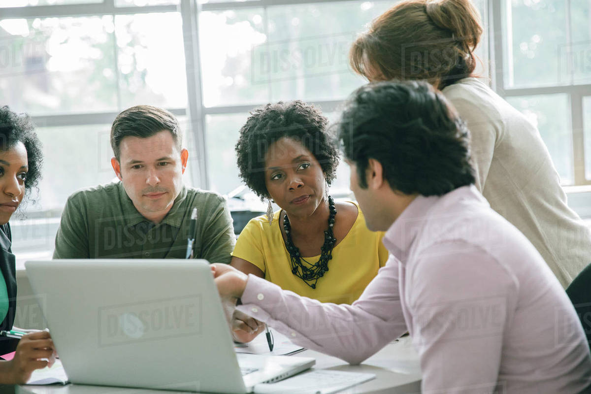 Business people holding a meeting around a computer in an office ...