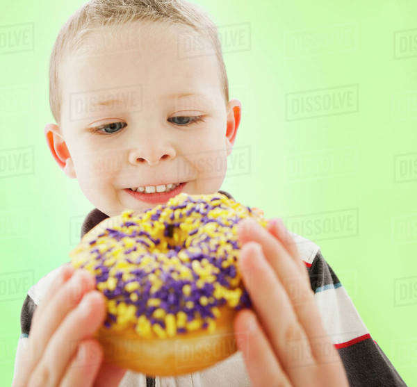Caucasian boy eating donut - Stock Photo - Dissolve