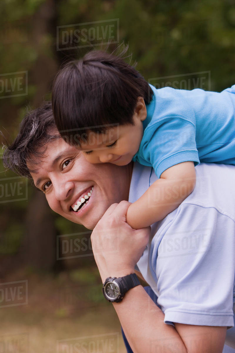 Smiling father giving piggyback to baby boy - Stock Photo - Dissolve