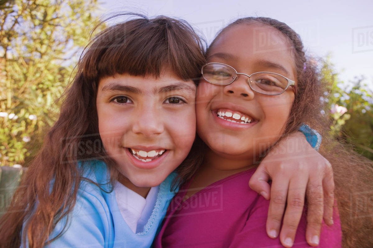 Hispanic girls hugging outdoors - Royalty-free Stock Photo | Dissolve