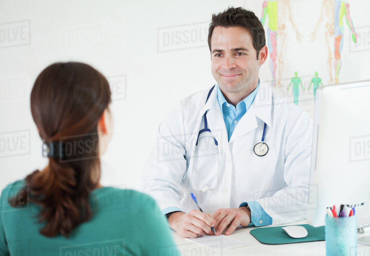 Doctor sitting at desk with patient - Royalty-free Stock Photo | Dissolve