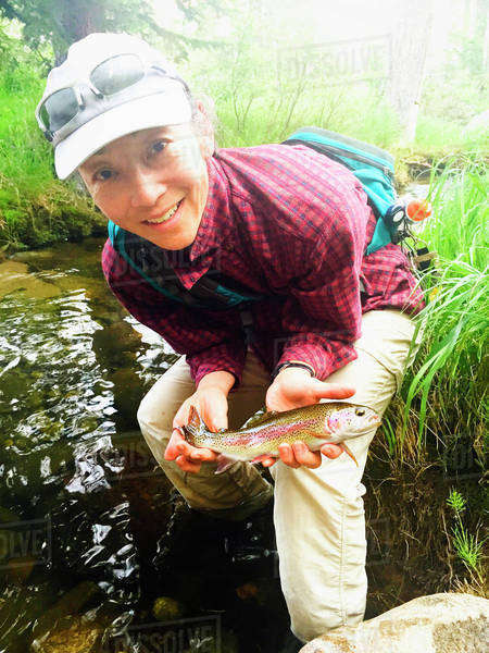 Japanese woman holding fish in stream - Stock Photo - Dissolve