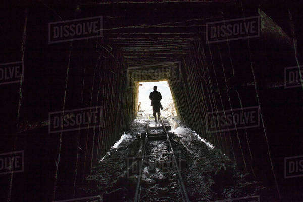 Mari man walking on tracks in mine - Stock Photo - Dissolve