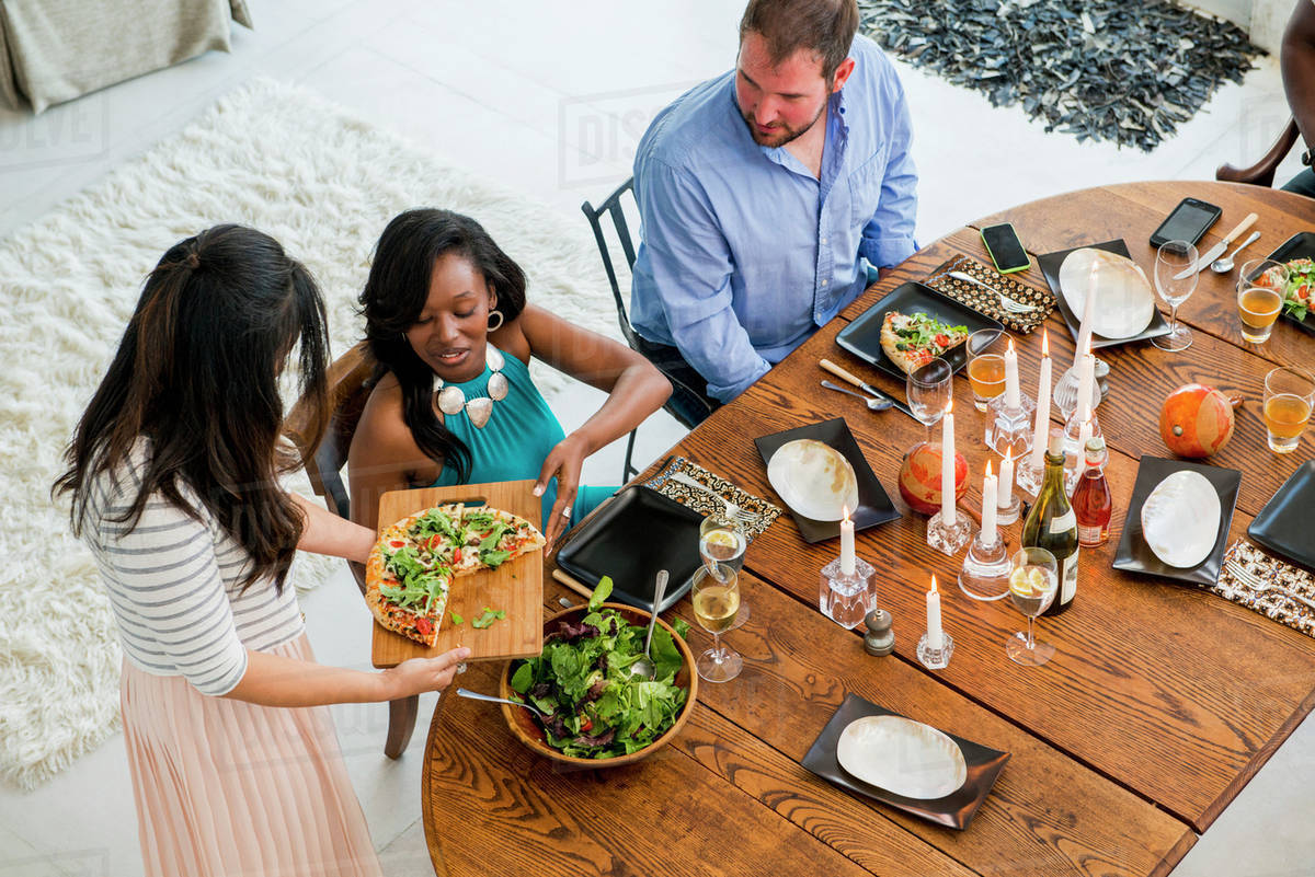 Woman serving friends at dinner party - Stock Photo - Dissolve