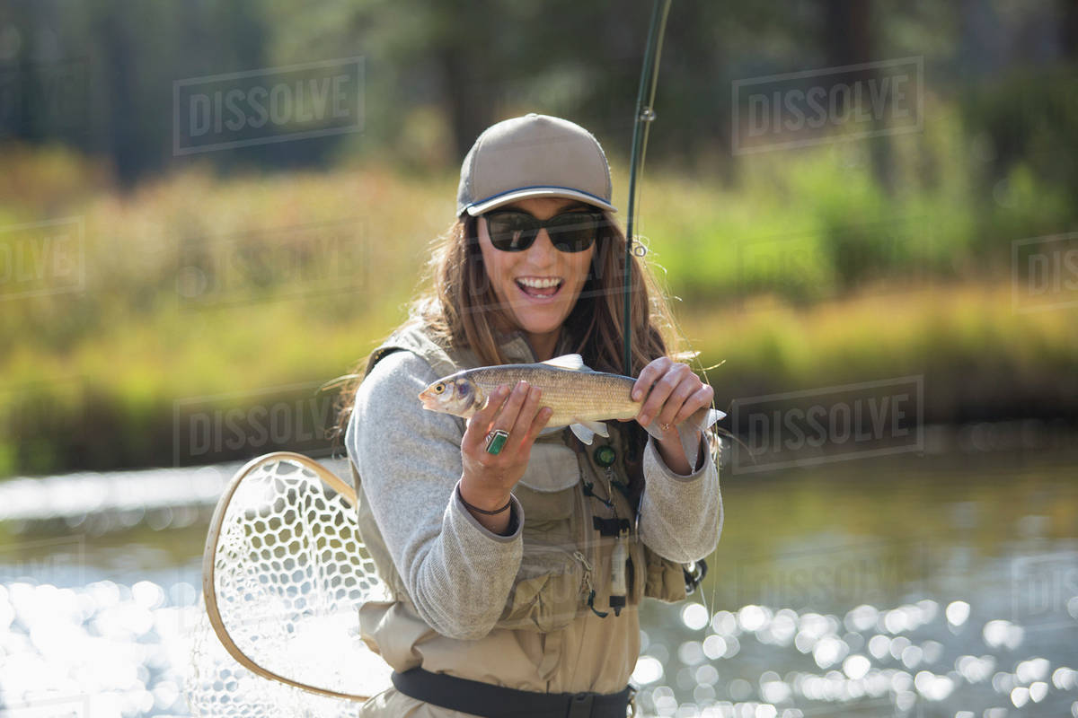 Caucasian woman displaying fishing catch - Stock Photo - Dissolve