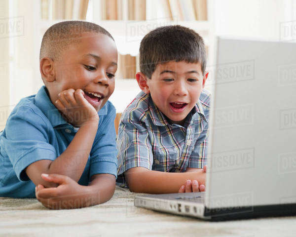 Smiling boys enjoying using a laptop - Stock Photo - Dissolve