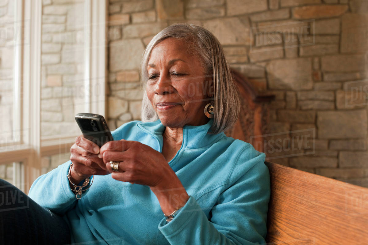 Black woman text messaging on cell phone - Stock Photo - Dissolve