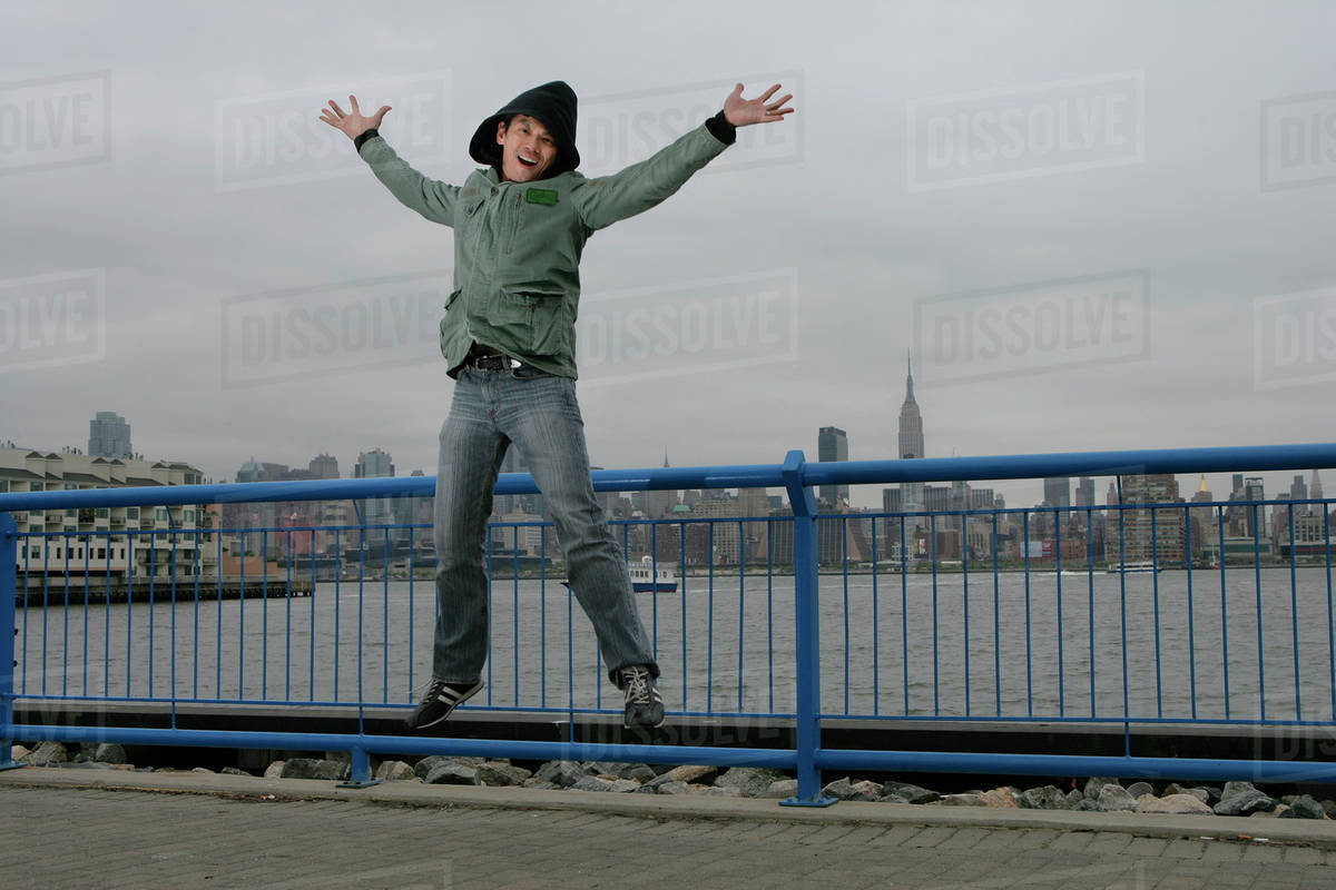 Happy Chinese man jumping on bridge - Stock Photo - Dissolve