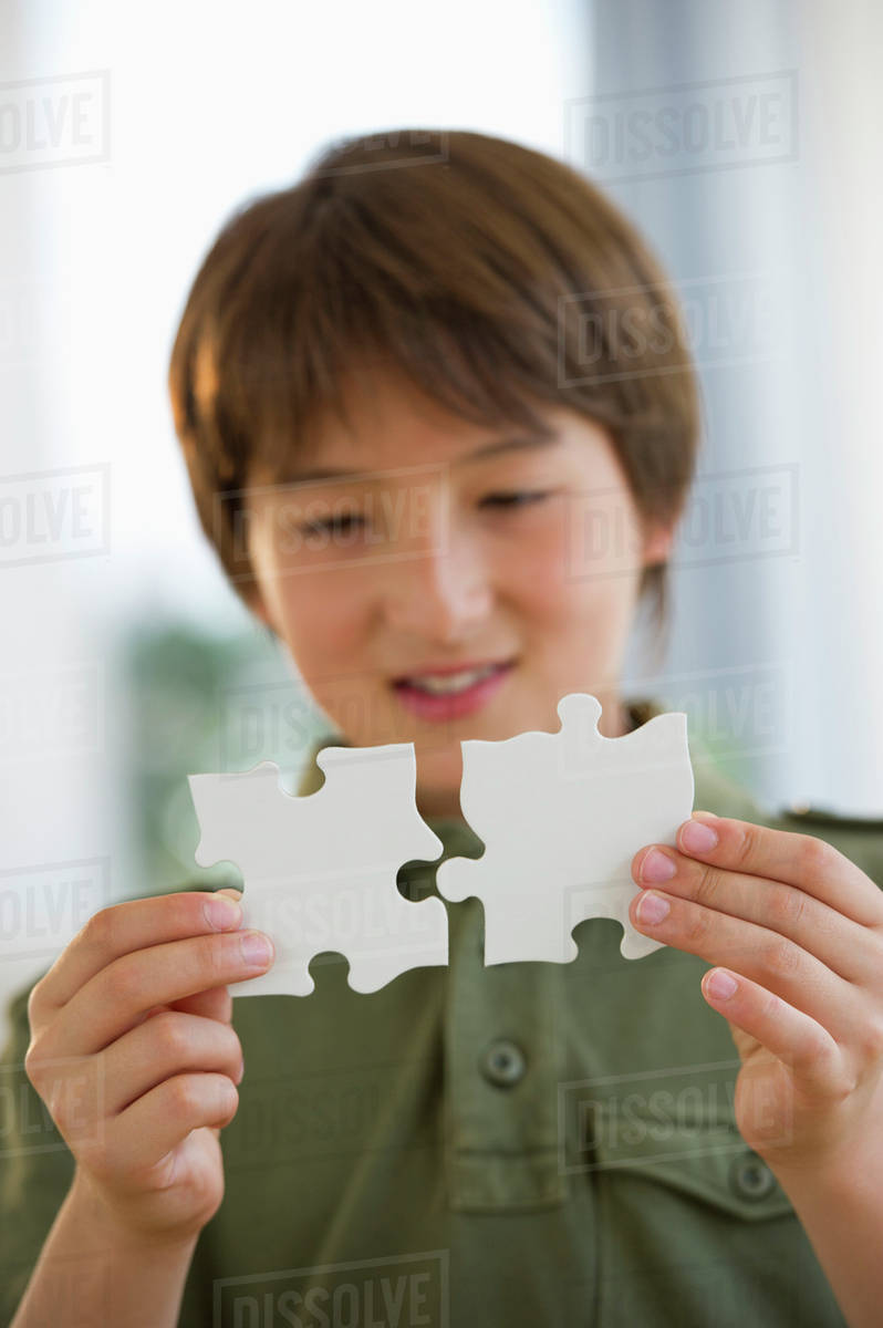 Mixed race boy connecting jigsaw pieces - Royalty-free Stock Photo ...