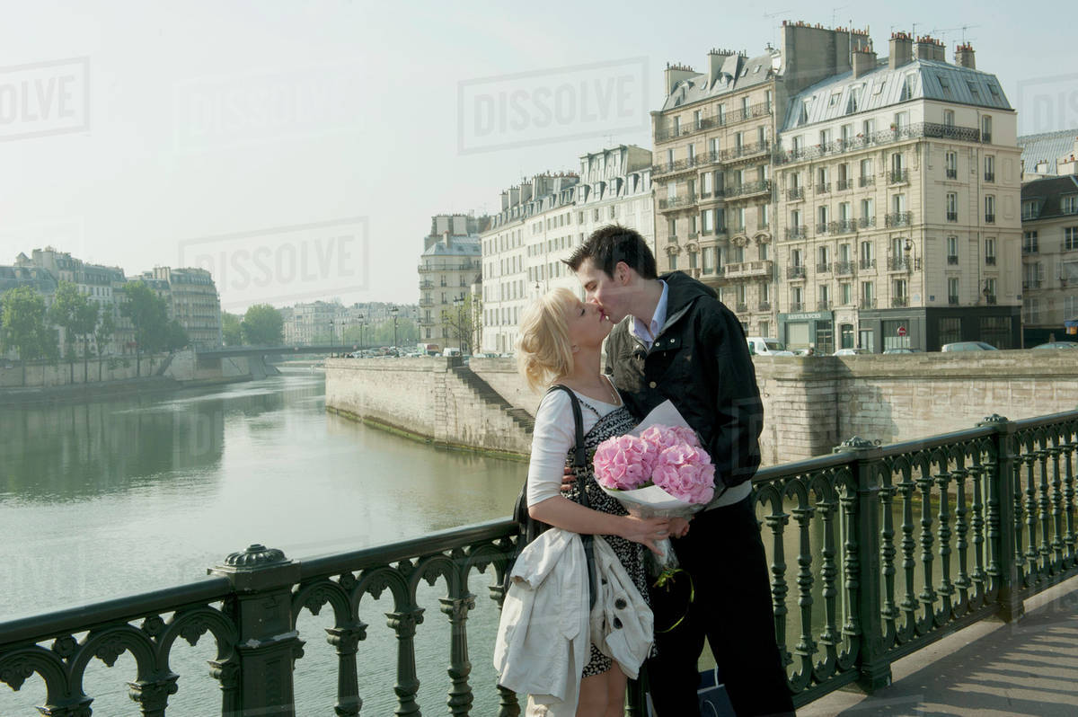 Caucasian couple kissing on bridge - Royalty-free Stock Photo | Dissolve