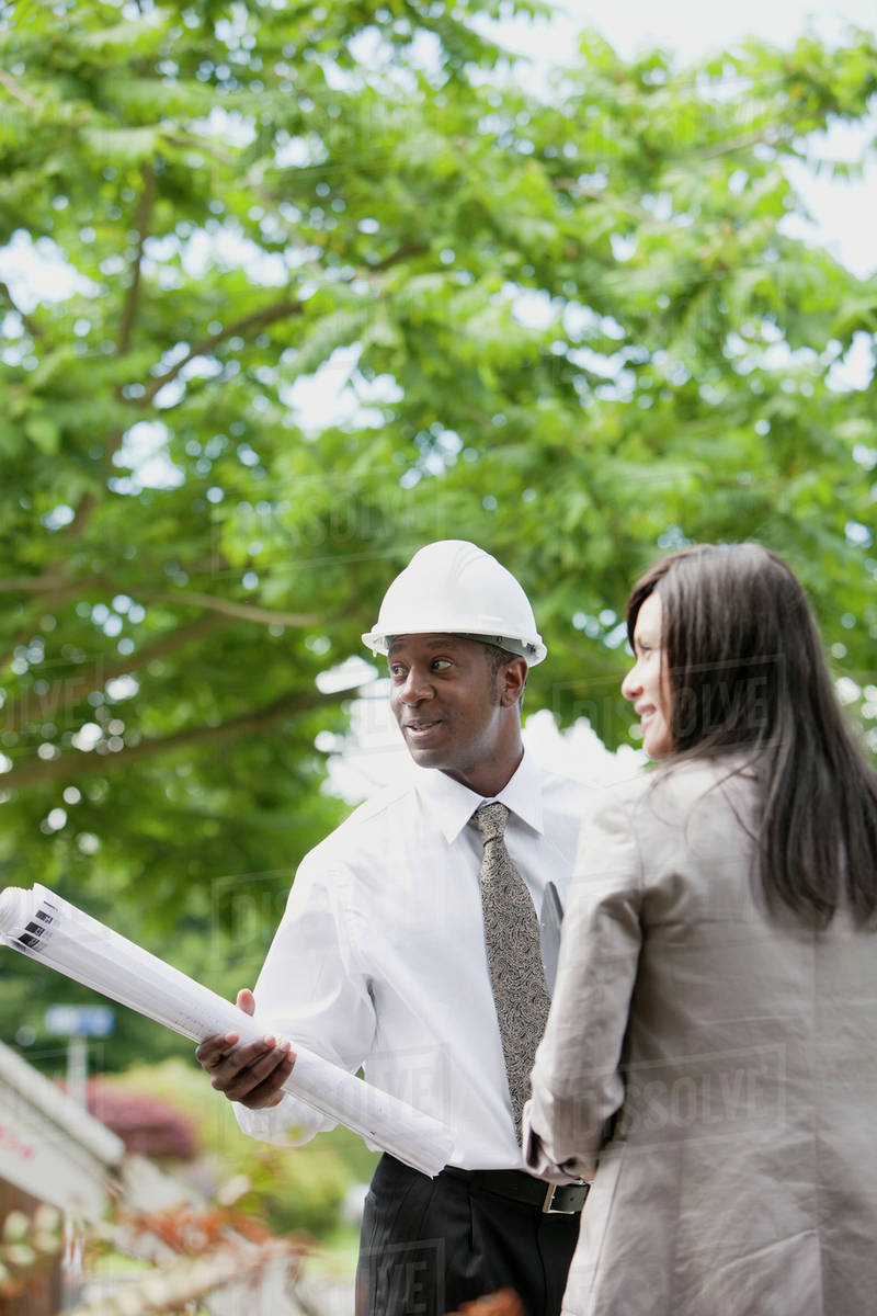 Woman talking to architect holding blueprints - Royalty-free Stock ...