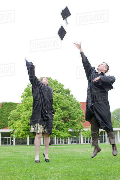 Graduates throwing graduation caps into air - Stock Photo - Dissolve
