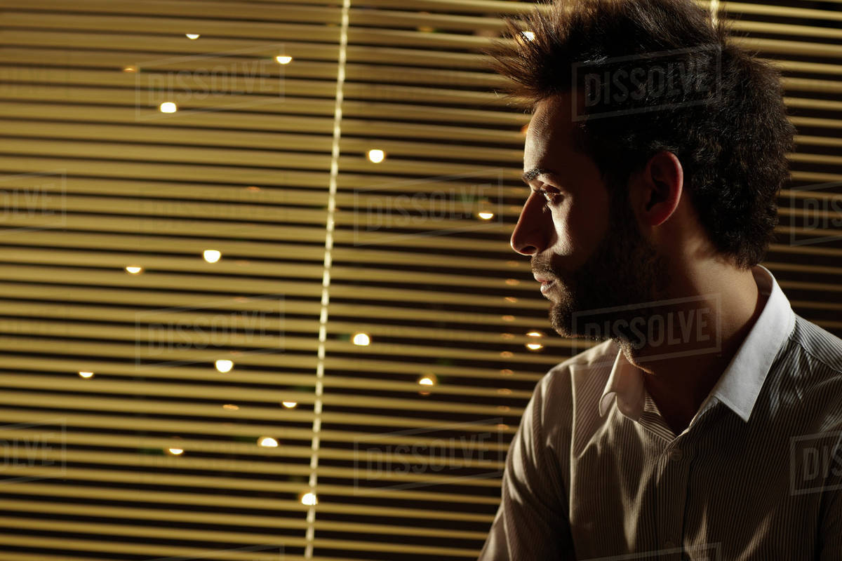 Caucasian man looking out window at night - Stock Photo - Dissolve