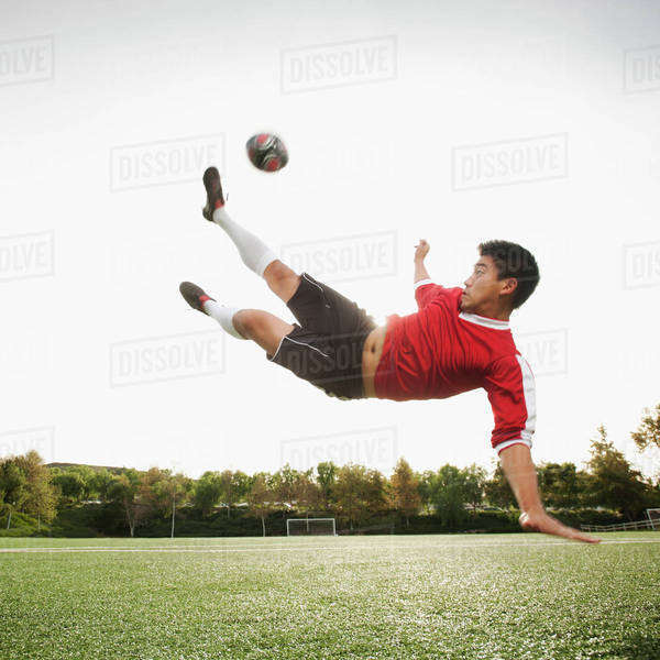 Asian soccer player in mid-air kicking soccer ball - Royalty-free Stock ...