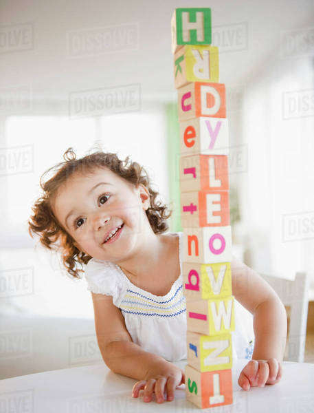 Mixed race girl stacking blocks - Stock Photo - Dissolve