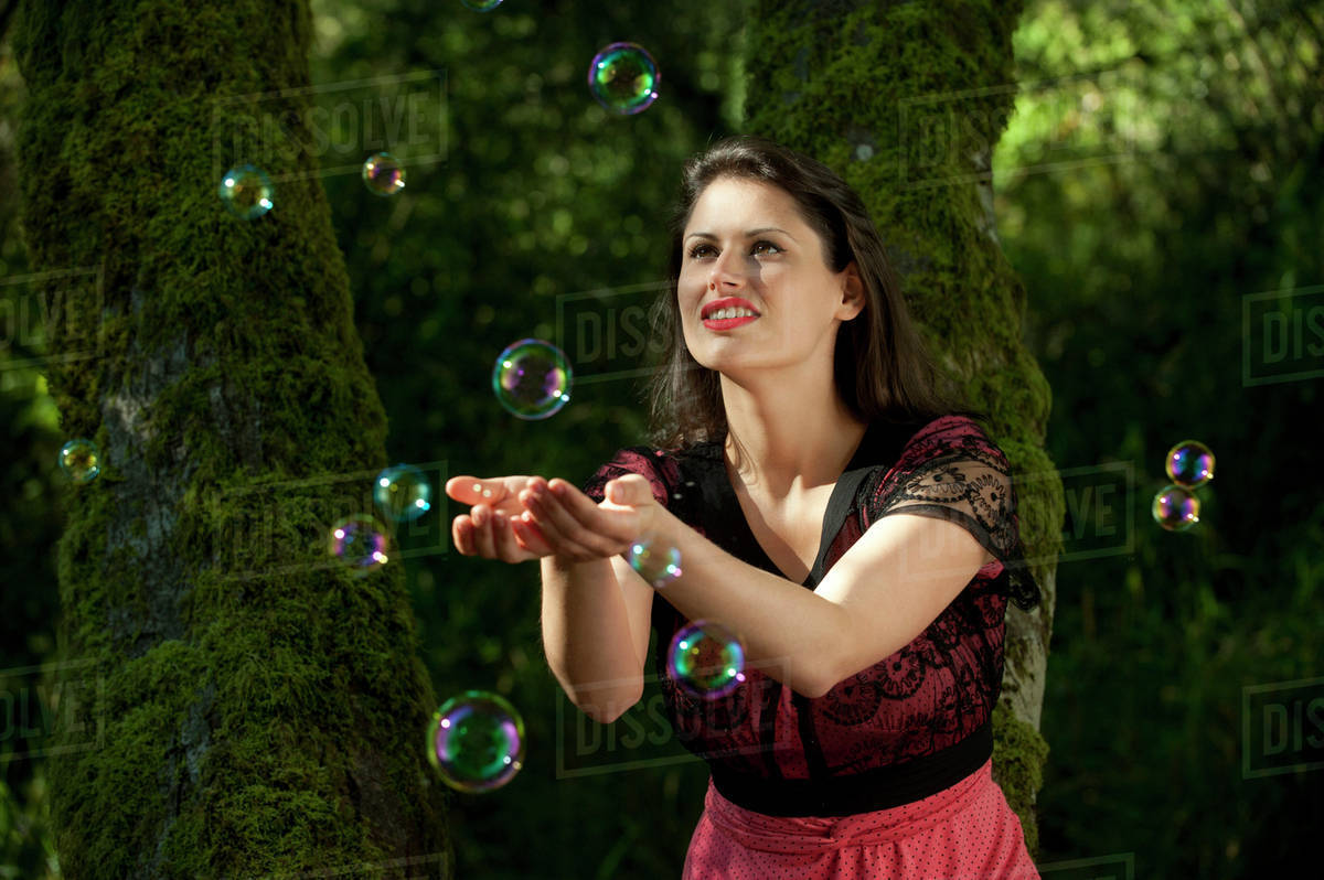Caucasian woman trying to catch bubbles in her hands - Royalty-free ...